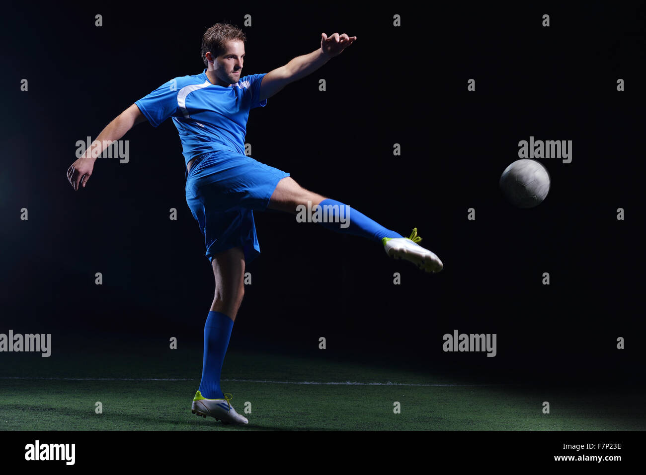 soccer player doing kick with ball on football stadium field isolated ...