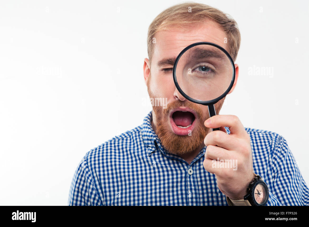 Portrait of casual man looking through magnifying glass at camera ...