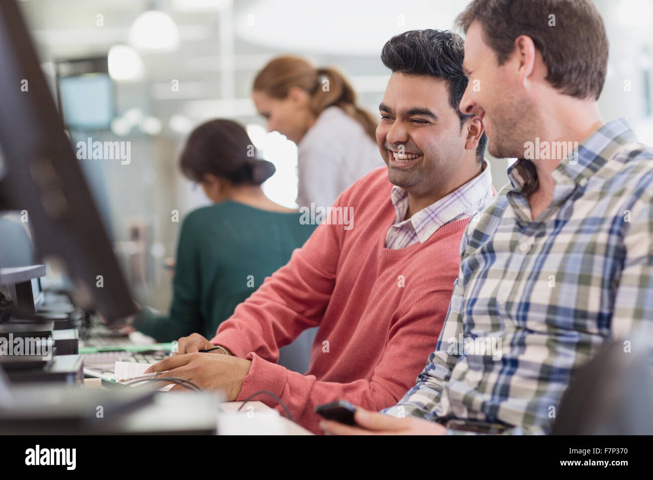 Men laughing at computer in adult education classroom Stock Photo - Alamy