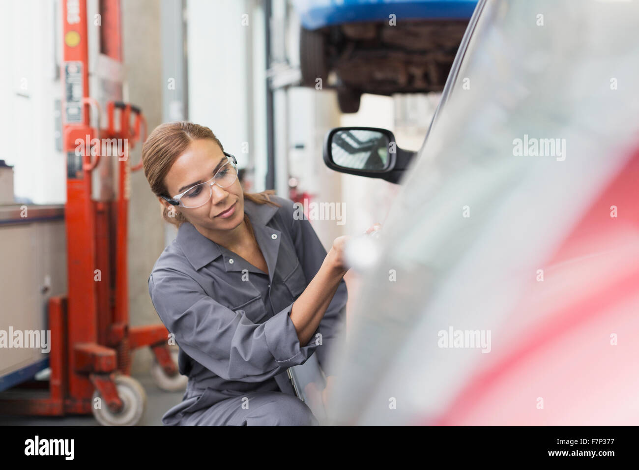 Female mechanic examining car in auto repair shop Stock Photo - Alamy