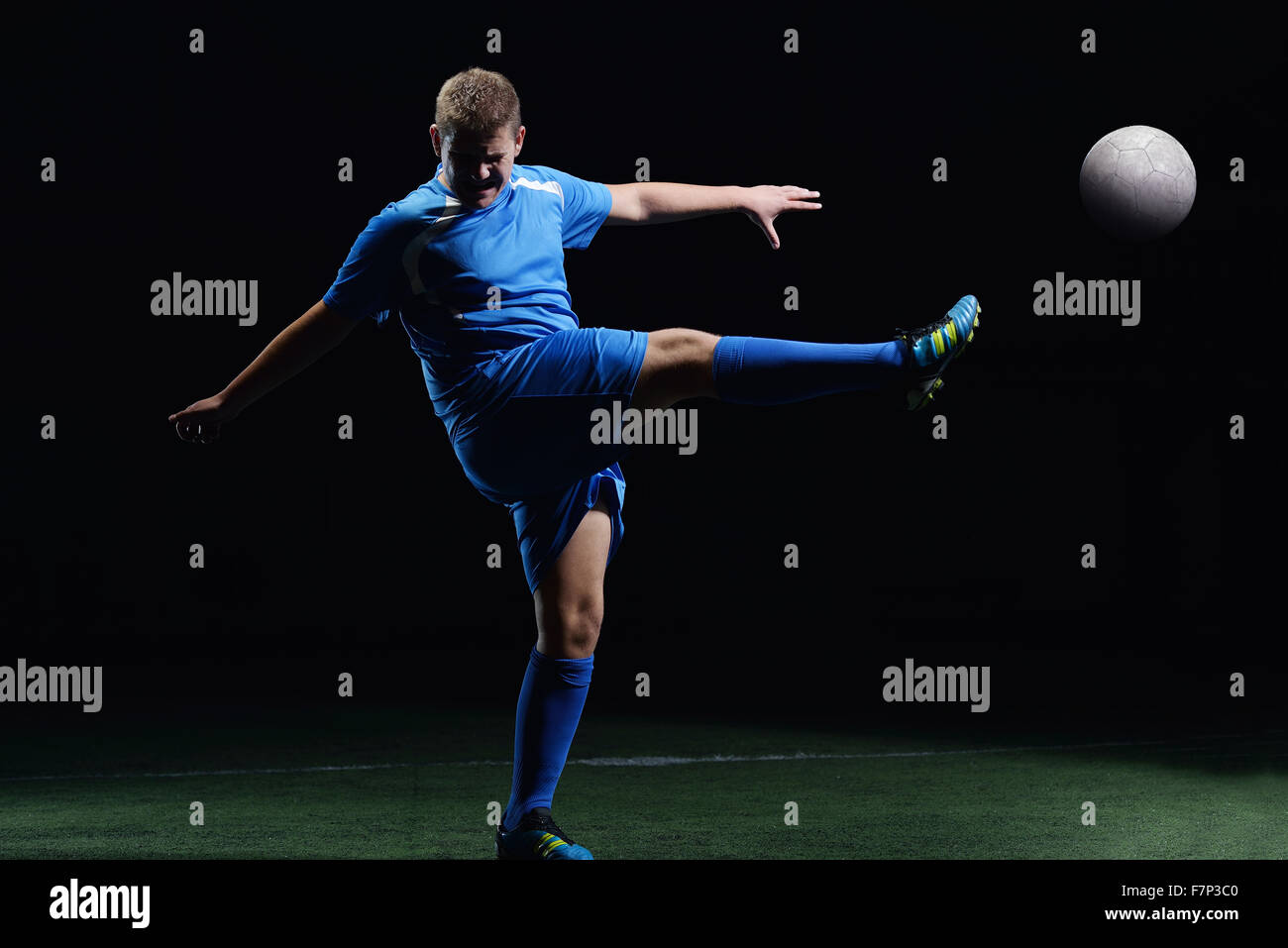 soccer player doing kick with ball on football stadium field isolated ...