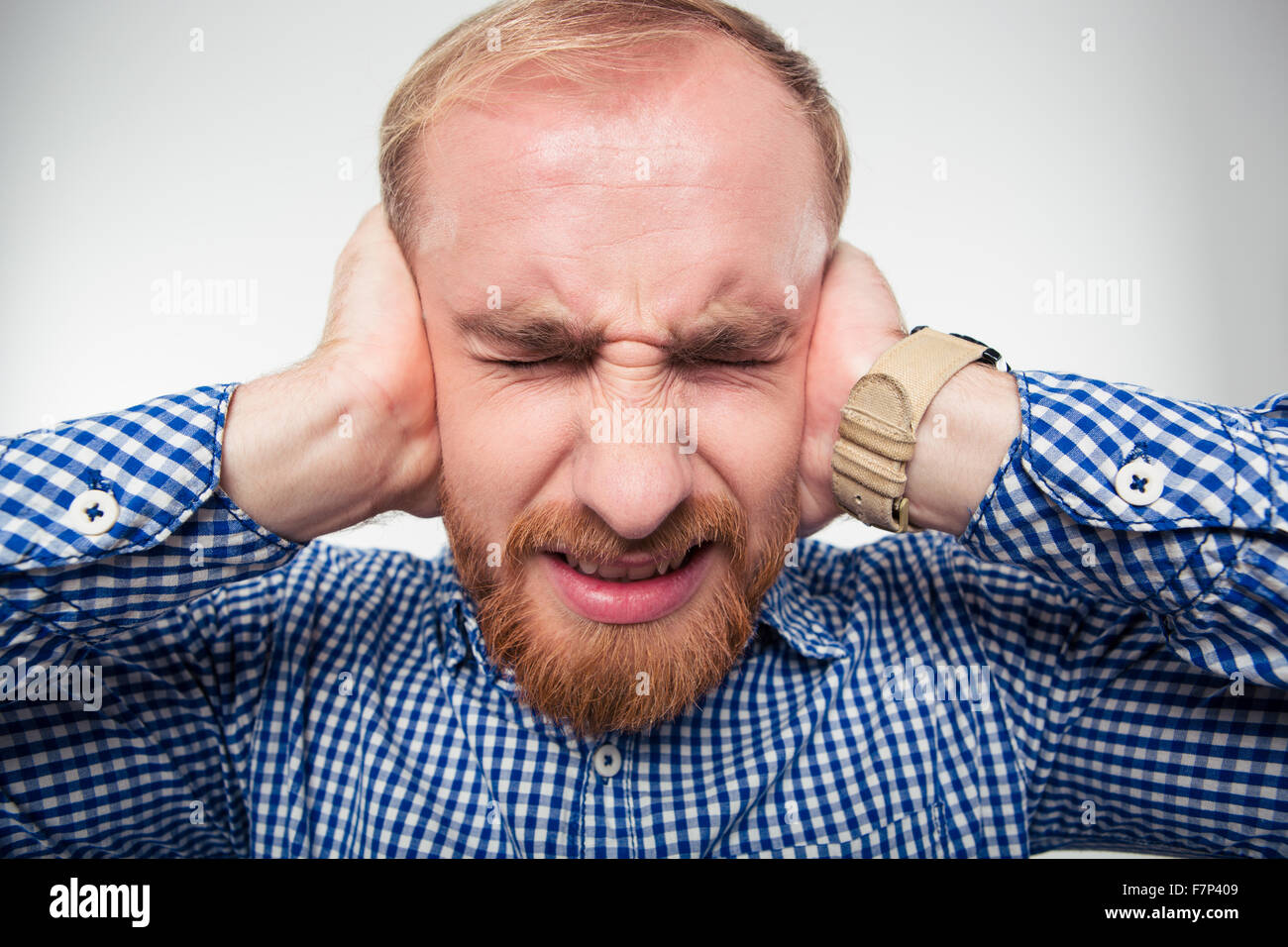 Portrait of a young man covering his ears isolated on a white ...