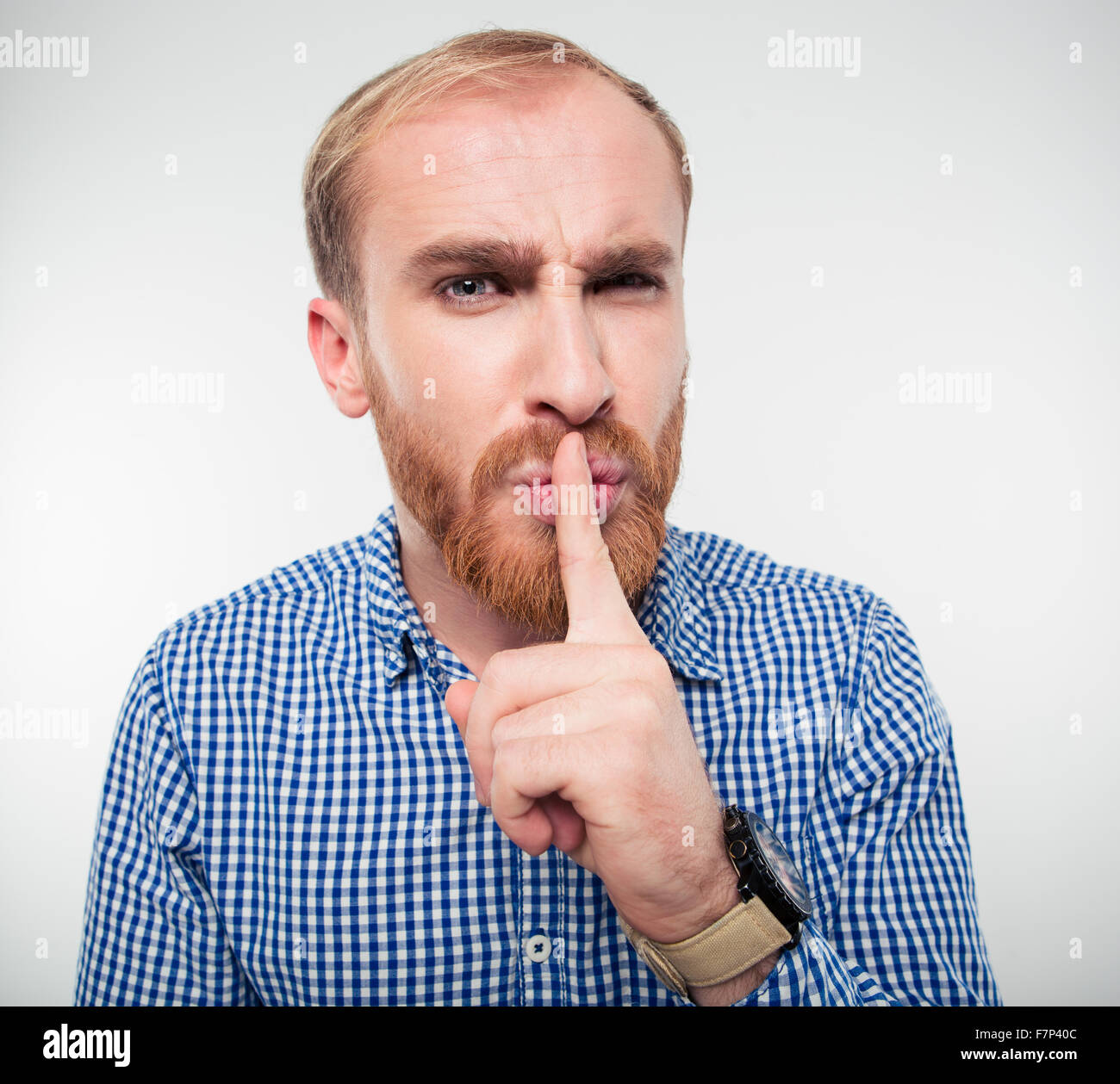 Portrait of a young casual man showing finger over lips isolated on a ...