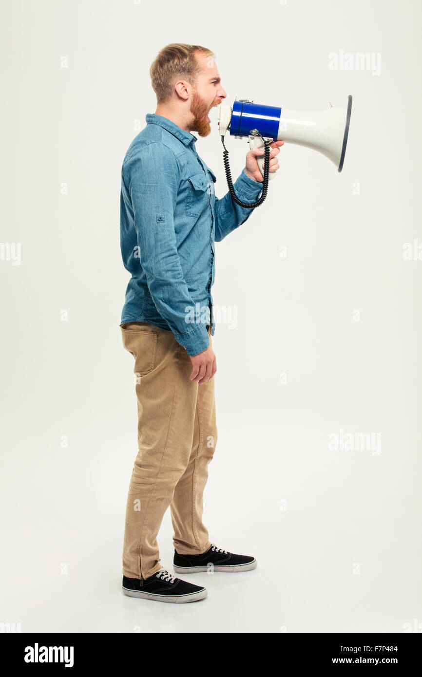 Side view portrait of a casual man screaming in megaphone isolated on a ...