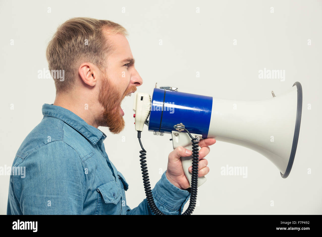 Side view portrait of a casual man yelling into megaphone isolated on a ...