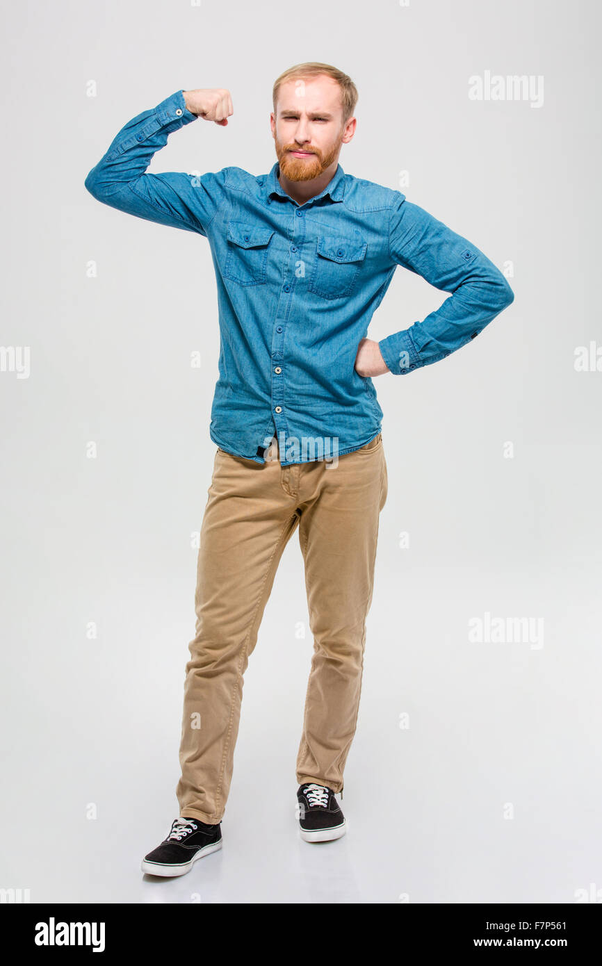 Full length portrait of amusing bearded young man showing his biceps ...