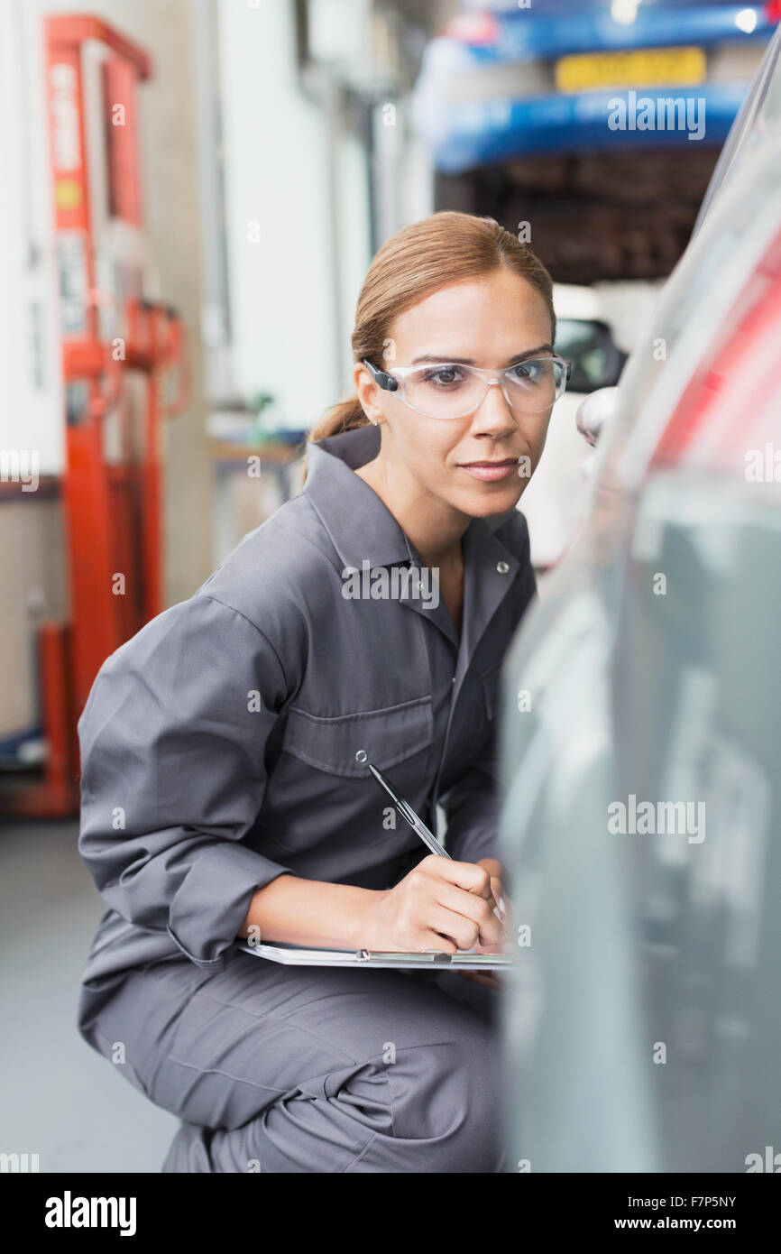Focused female mechanic taking notes in auto repair shop Stock Photo ...