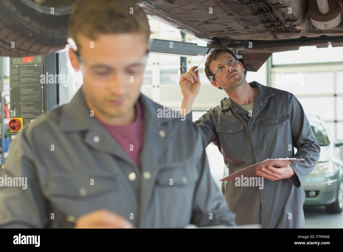 Mechanic with clipboard working under car in auto repair shop Stock ...