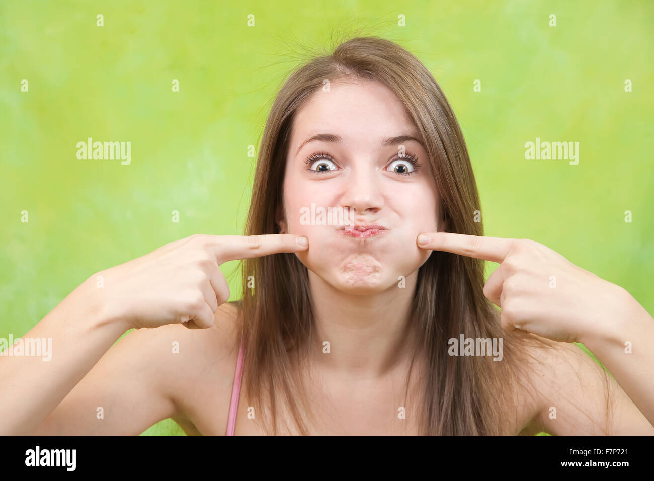 girl puffs up her cheeks over green background Stock Photo - Alamy