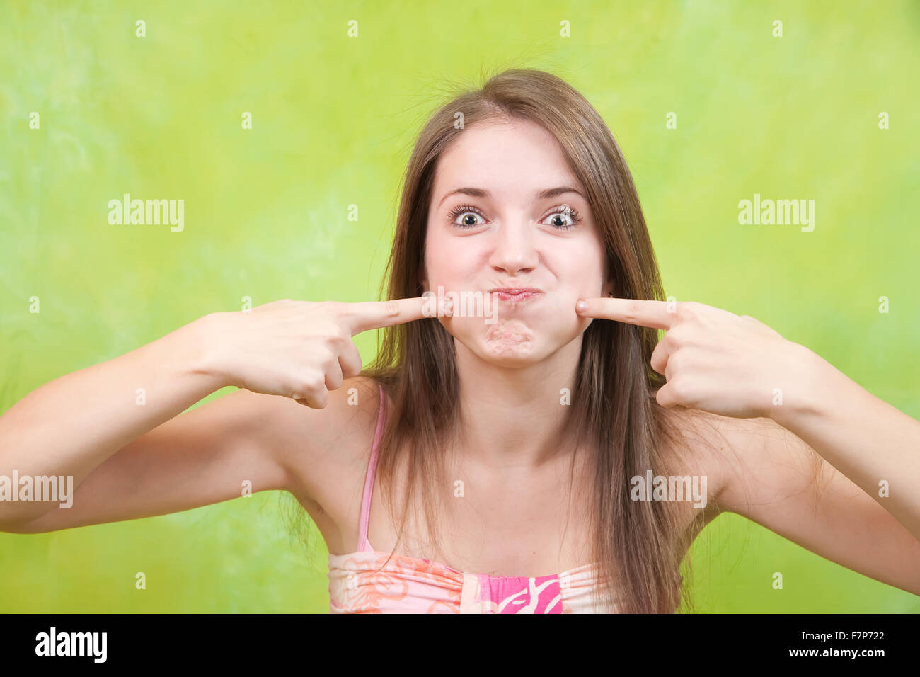 girl puffs up her cheeks over green background Stock Photo - Alamy