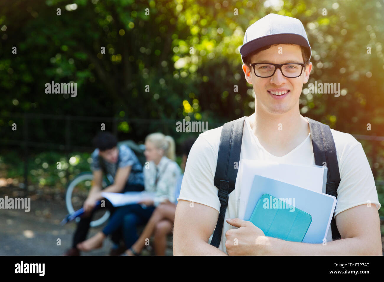 Portrait smiling college student with books in park Stock Photo - Alamy