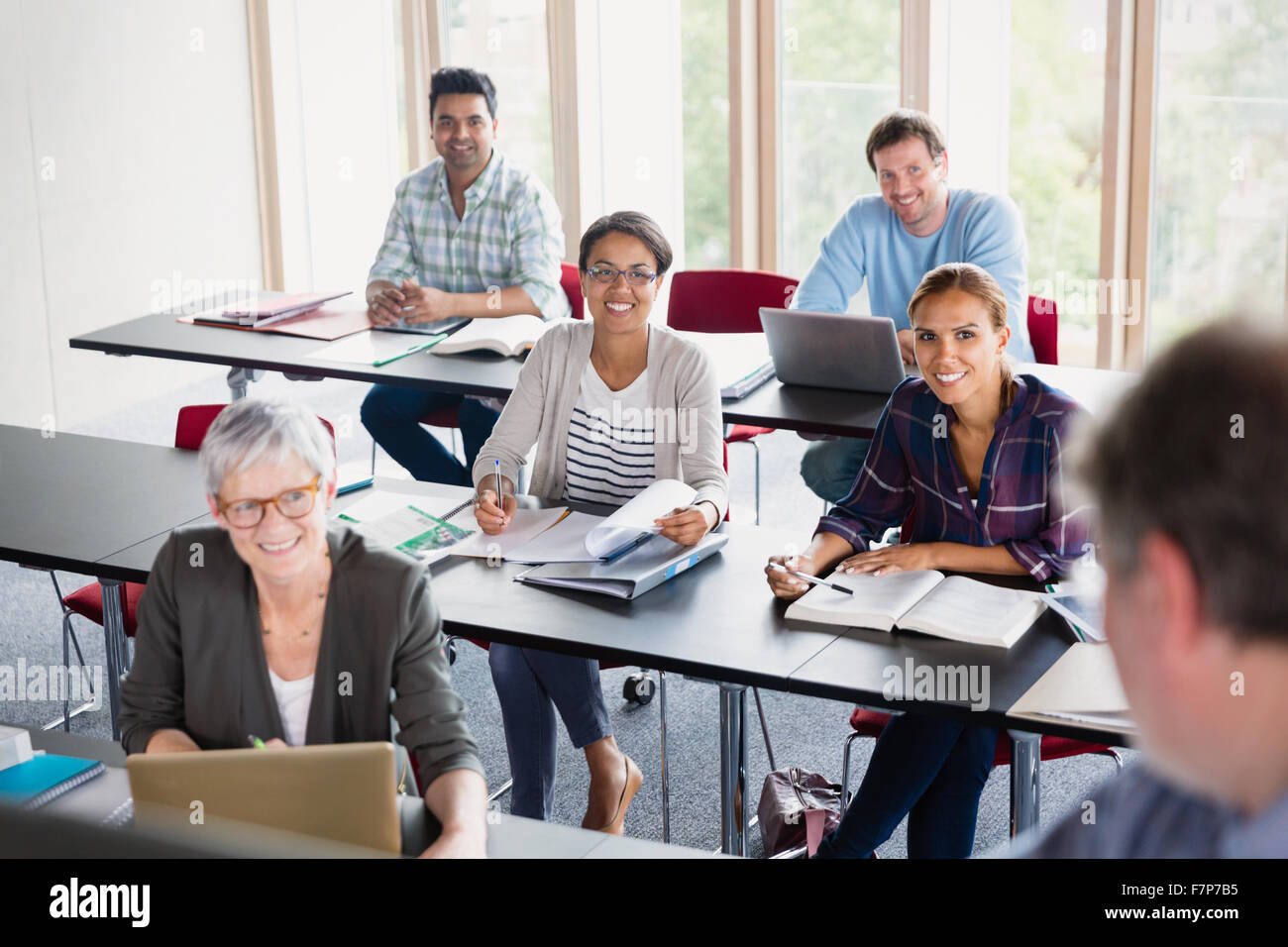 Smiling students watching teacher in adult education classroom Stock ...