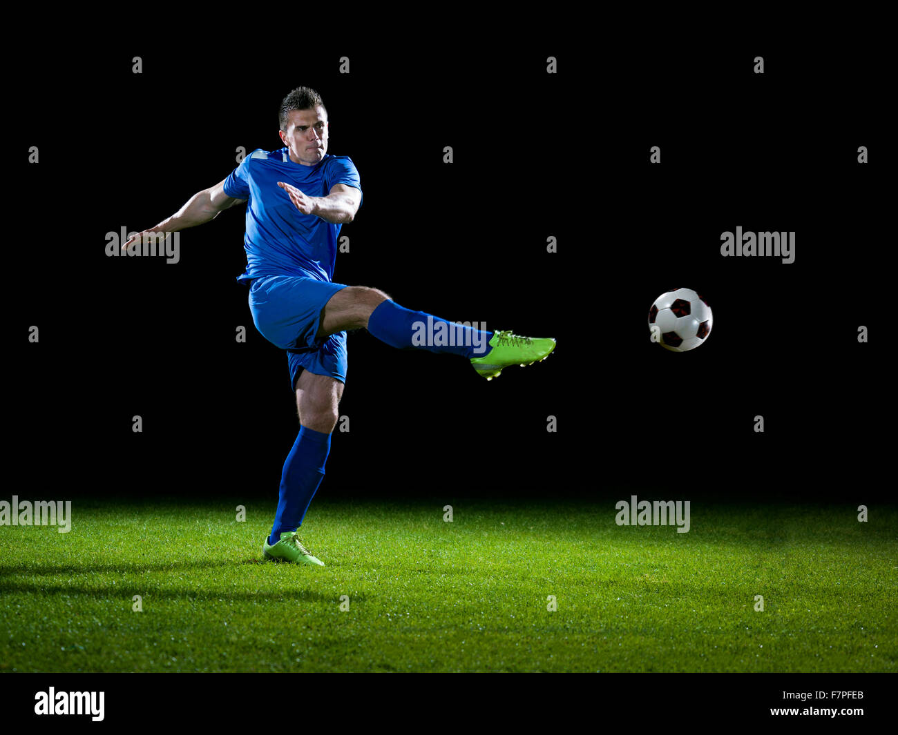 soccer player doing kick with ball on football stadium field isolated ...