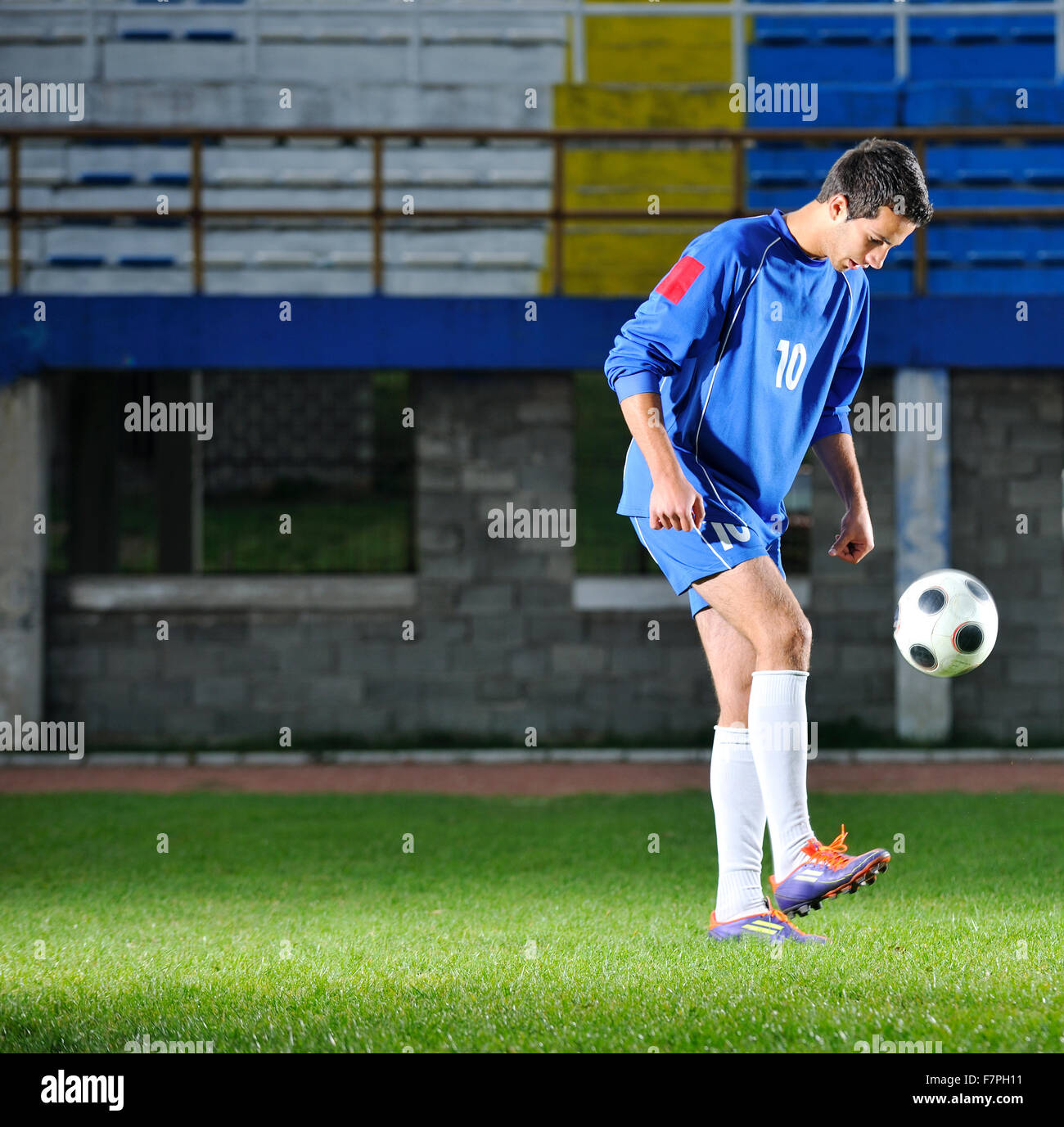 soccer player doing kick with ball on football stadium field isolated ...