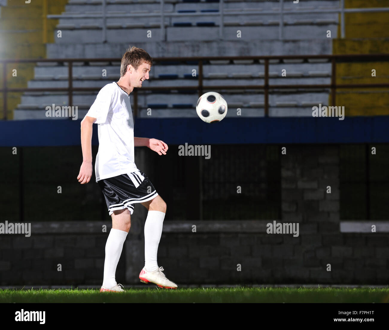 soccer player doing kick with ball on football stadium field isolated ...