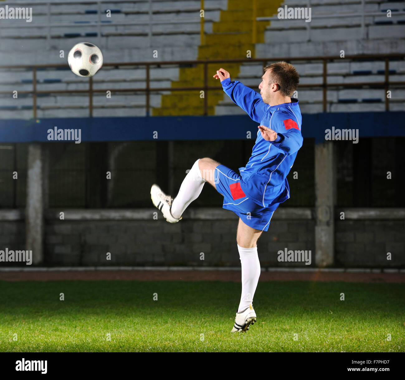 soccer player doing kick with ball on football stadium field isolated ...