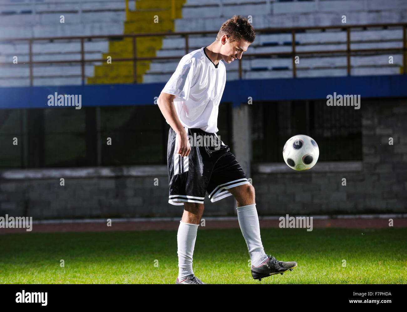 soccer player doing kick with ball on football stadium field isolated ...