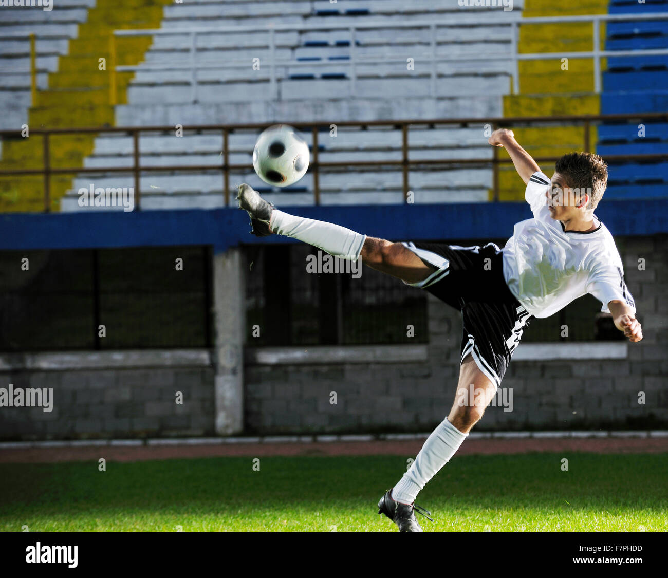 soccer player doing kick with ball on football stadium field isolated ...