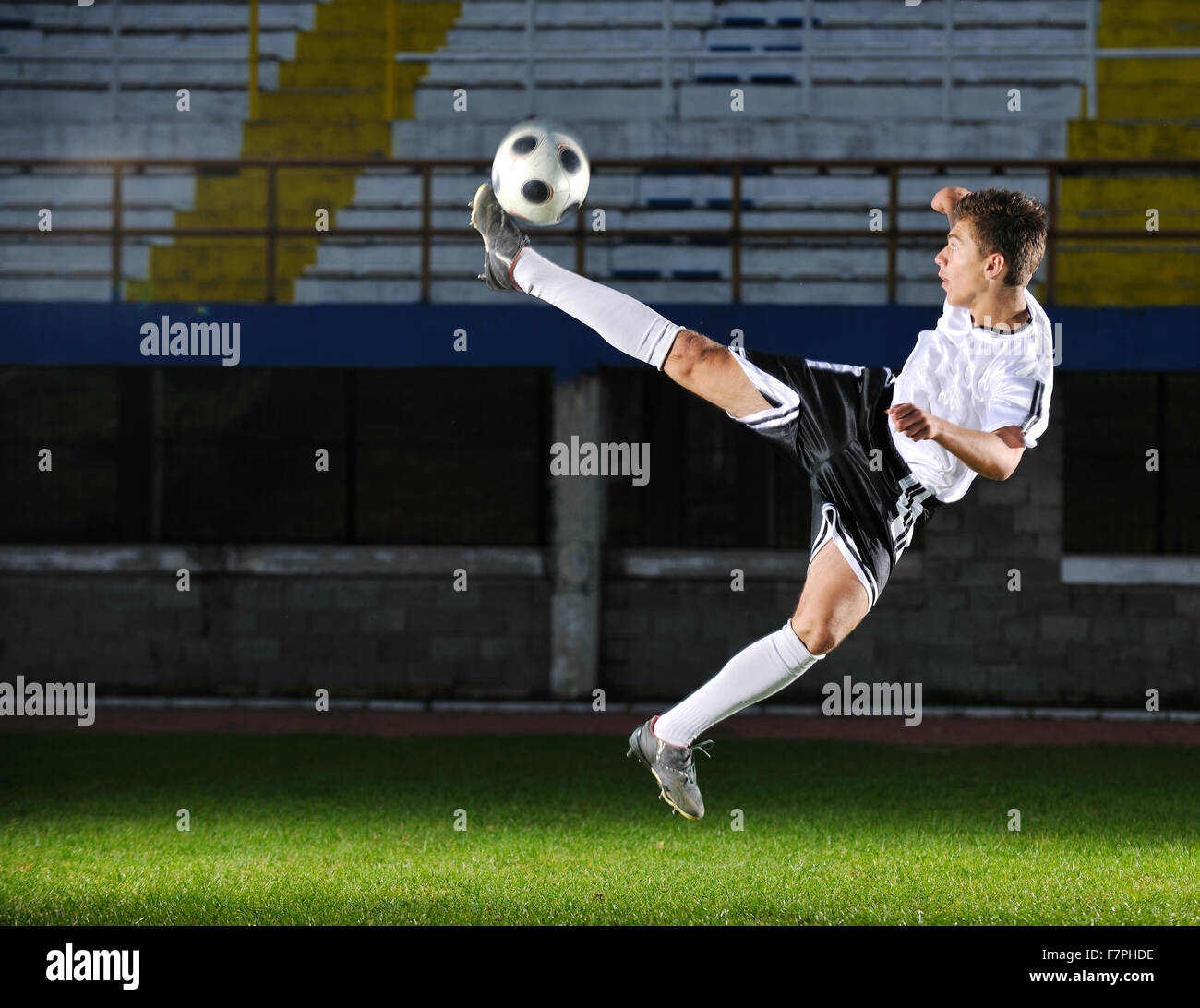 soccer player doing kick with ball on football stadium field isolated on black background in ...