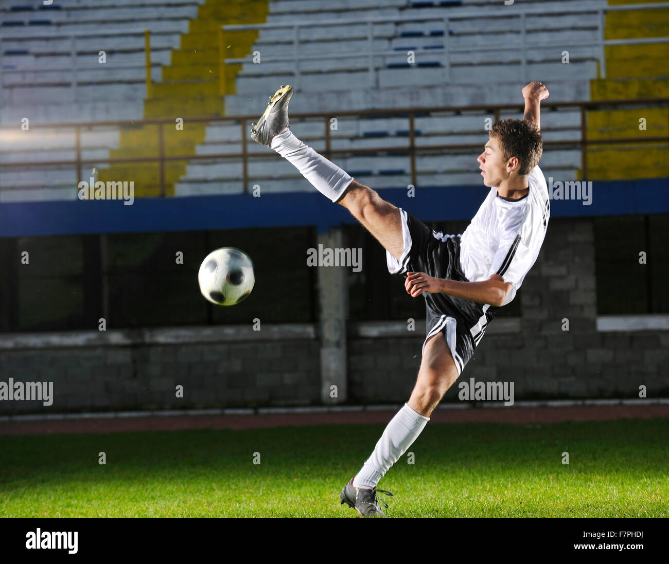 soccer player doing kick with ball on football stadium field isolated ...
