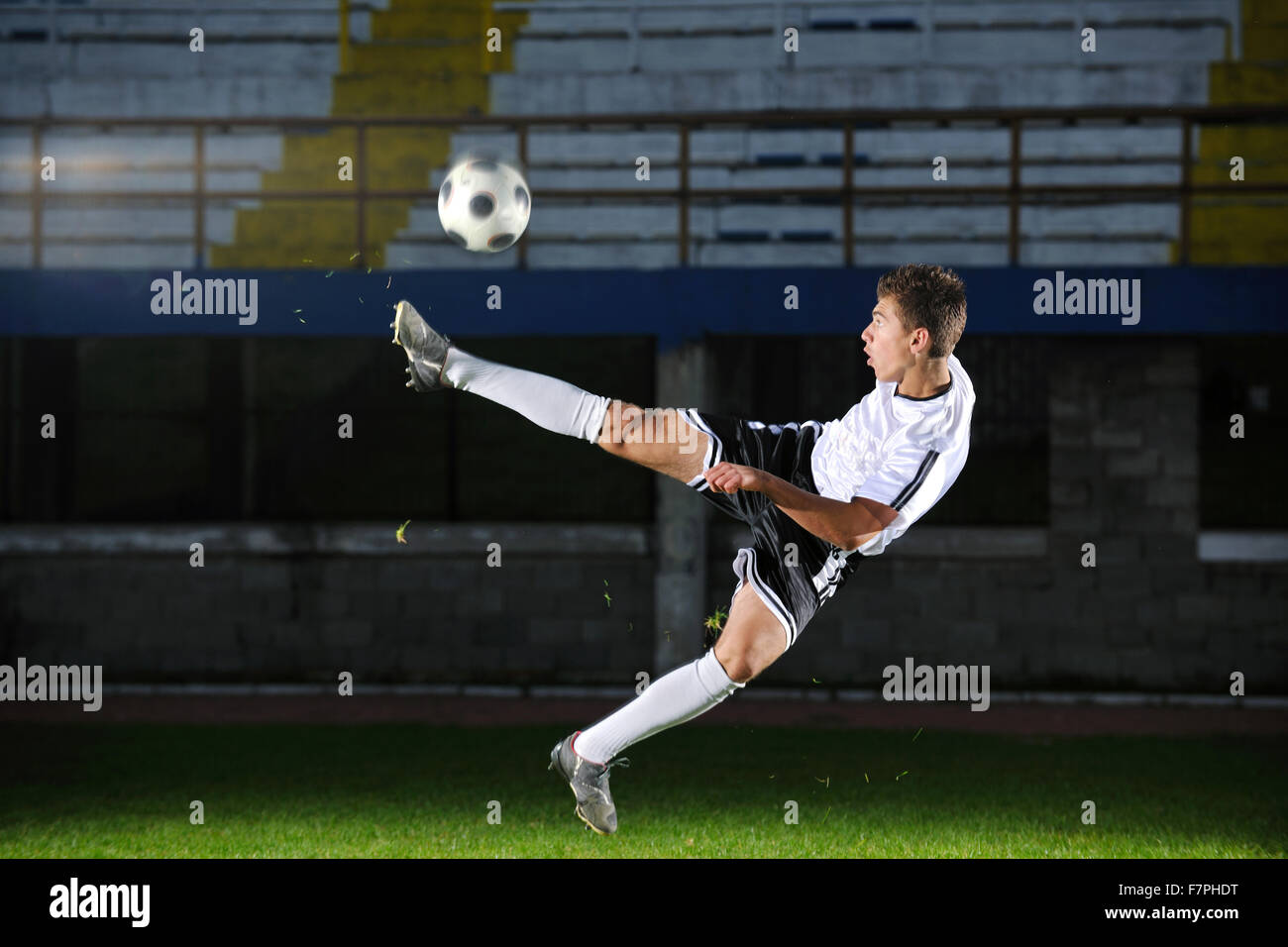 soccer player doing kick with ball on football stadium field isolated ...