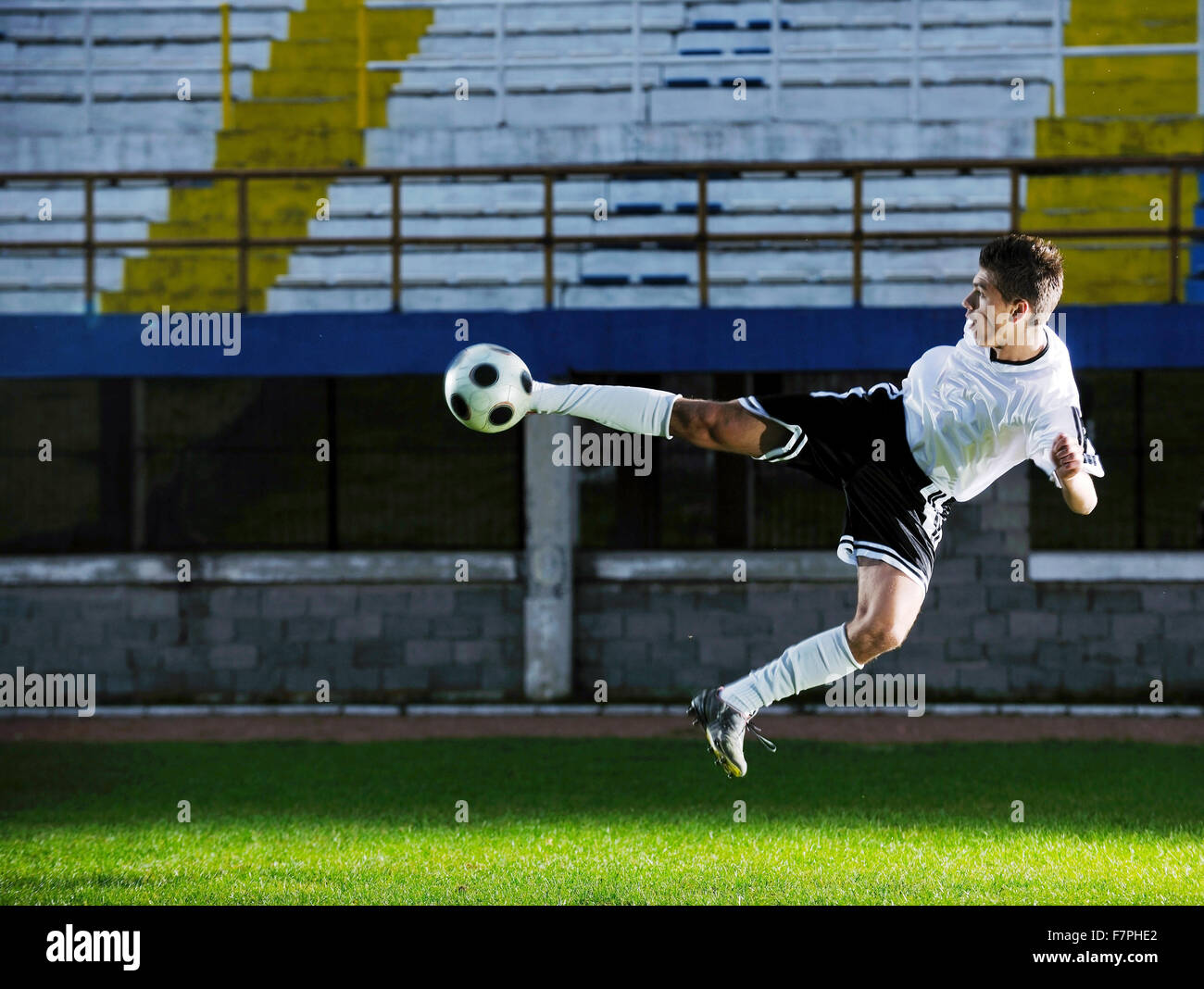 soccer player doing kick with ball on football stadium field isolated ...