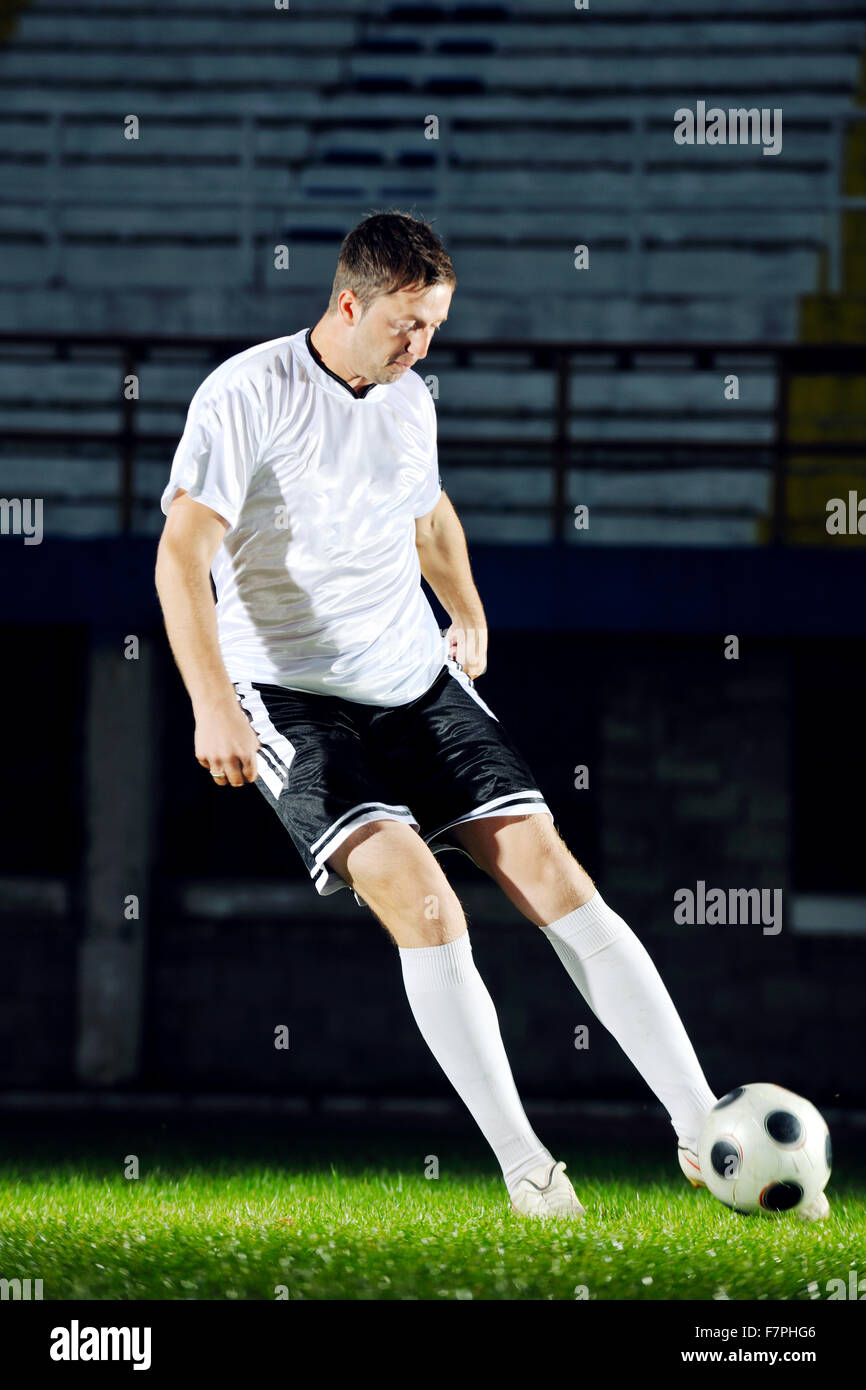 soccer player doing kick with ball on football stadium field isolated on black background in ...