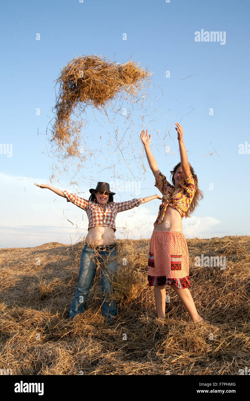 Happy girl throwing hay on background of the sky Stock Photo - Alamy