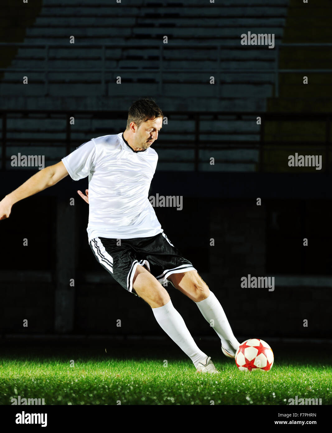 soccer player doing kick with ball on football stadium field isolated on black background in ...