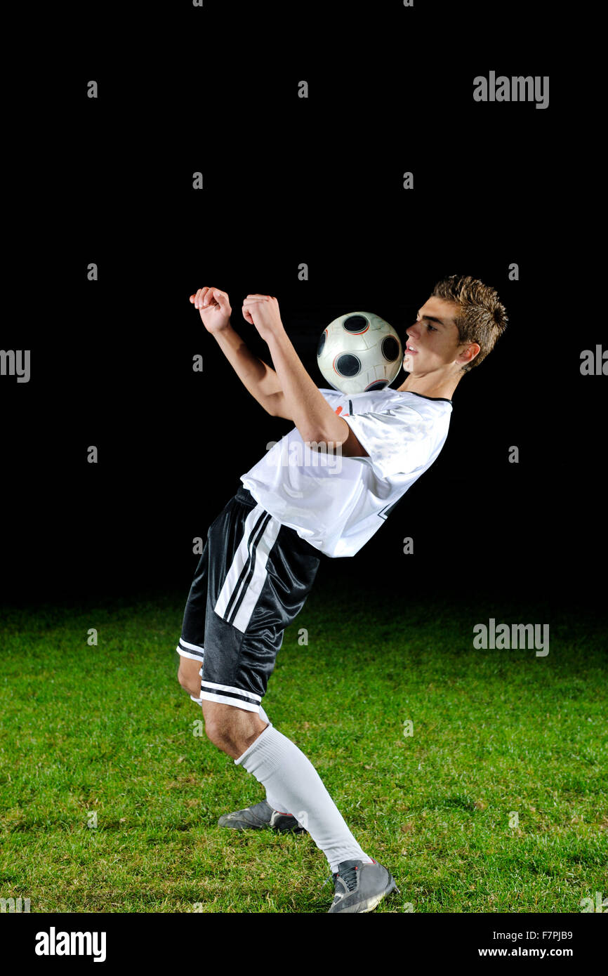 soccer player doing kick with ball on football stadium field isolated on black background in ...