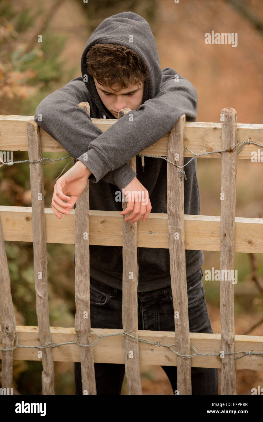 Sad Teenage Boy Leaning On A Fence Stock Photo - Alamy