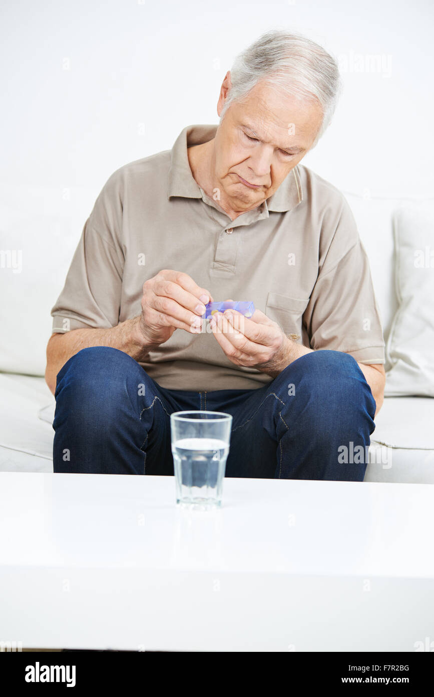 Old man sitting with medication and a glass of water at home Stock ...