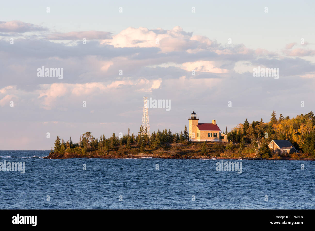 Lighthouse set on a peninsula and photographed in warm, evening light ...