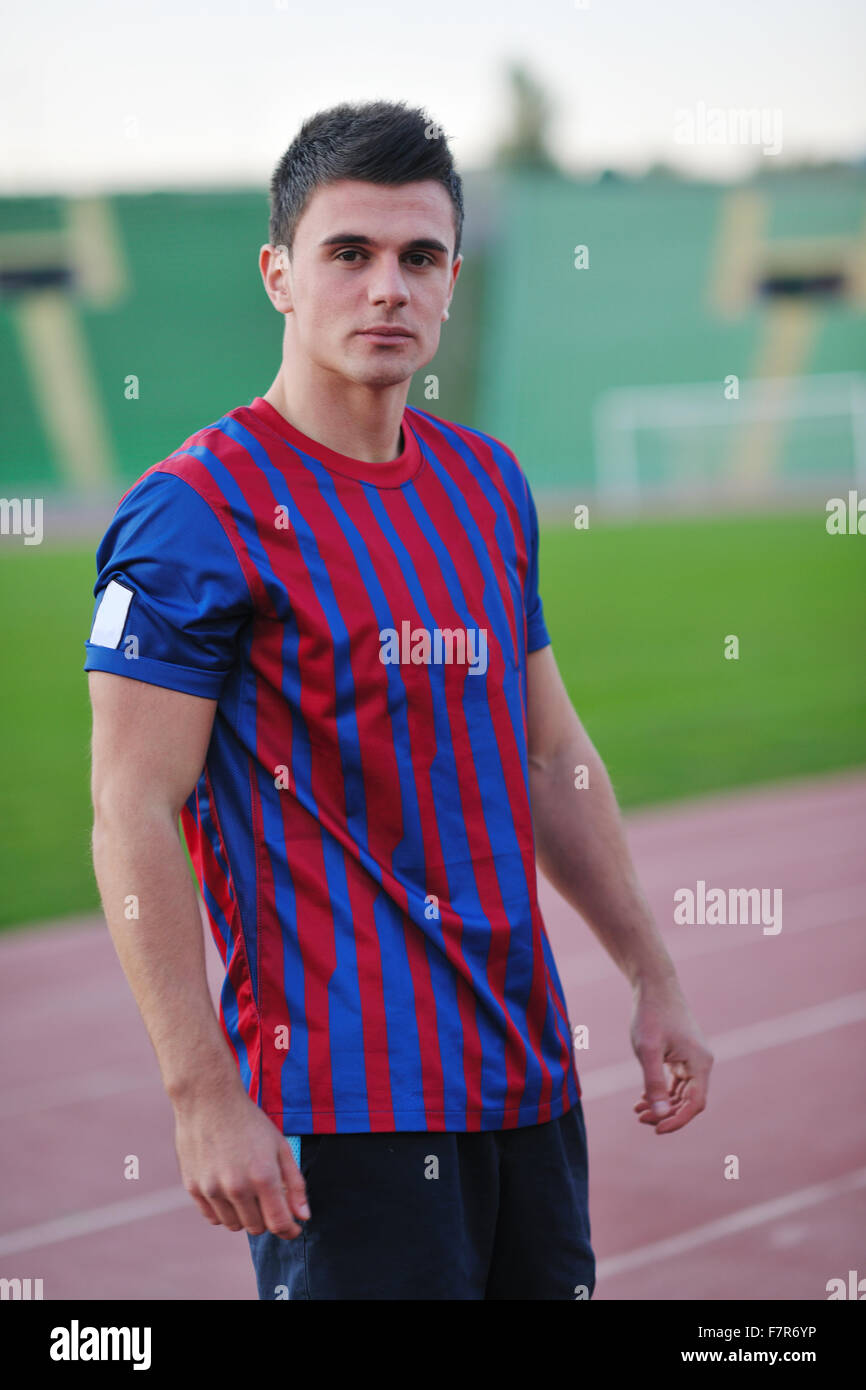 portrait of young handsome soccer player man at football stadium and ...