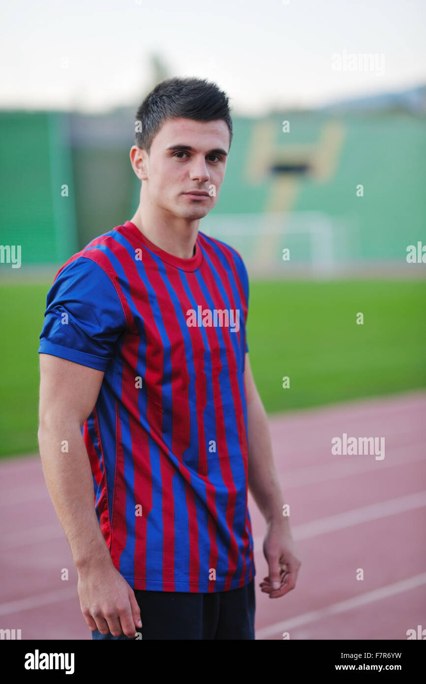 portrait of young handsome soccer player man at football stadium and ...