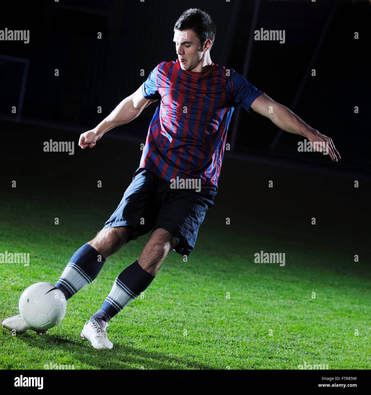 soccer player doing kick with ball on football stadium field isolated ...