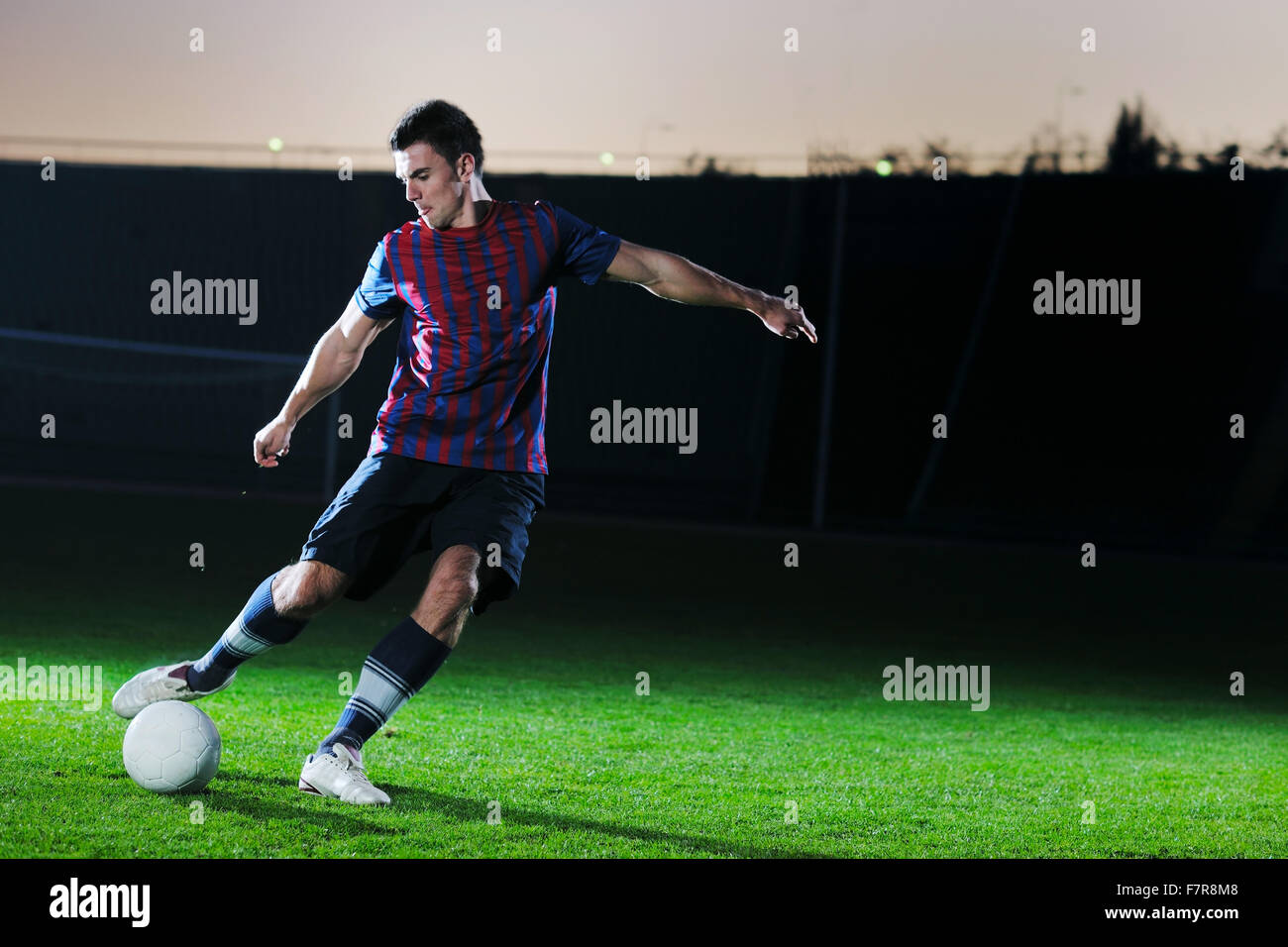soccer player doing kick with ball on football stadium field isolated ...