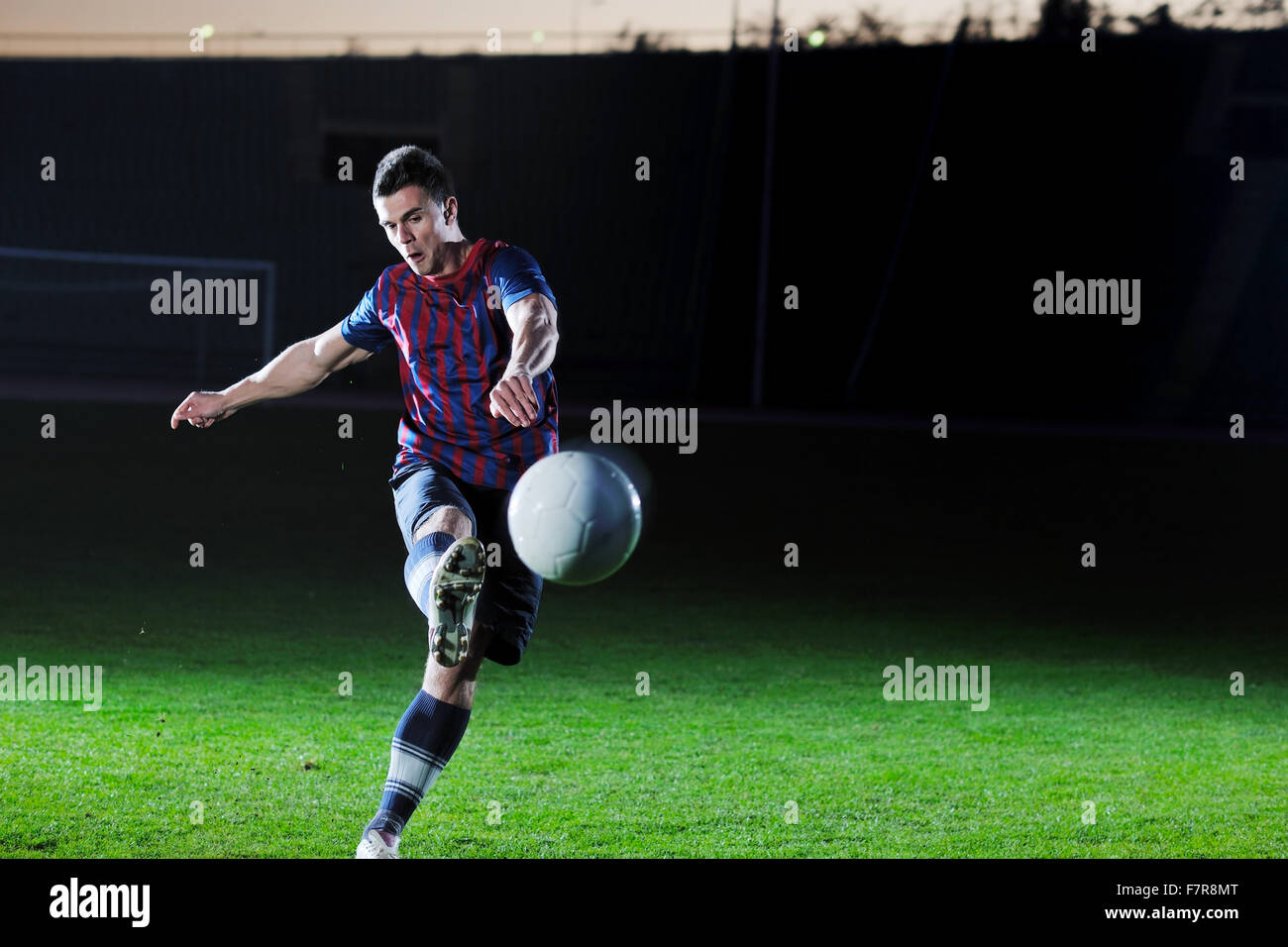 soccer player doing kick with ball on football stadium field isolated ...