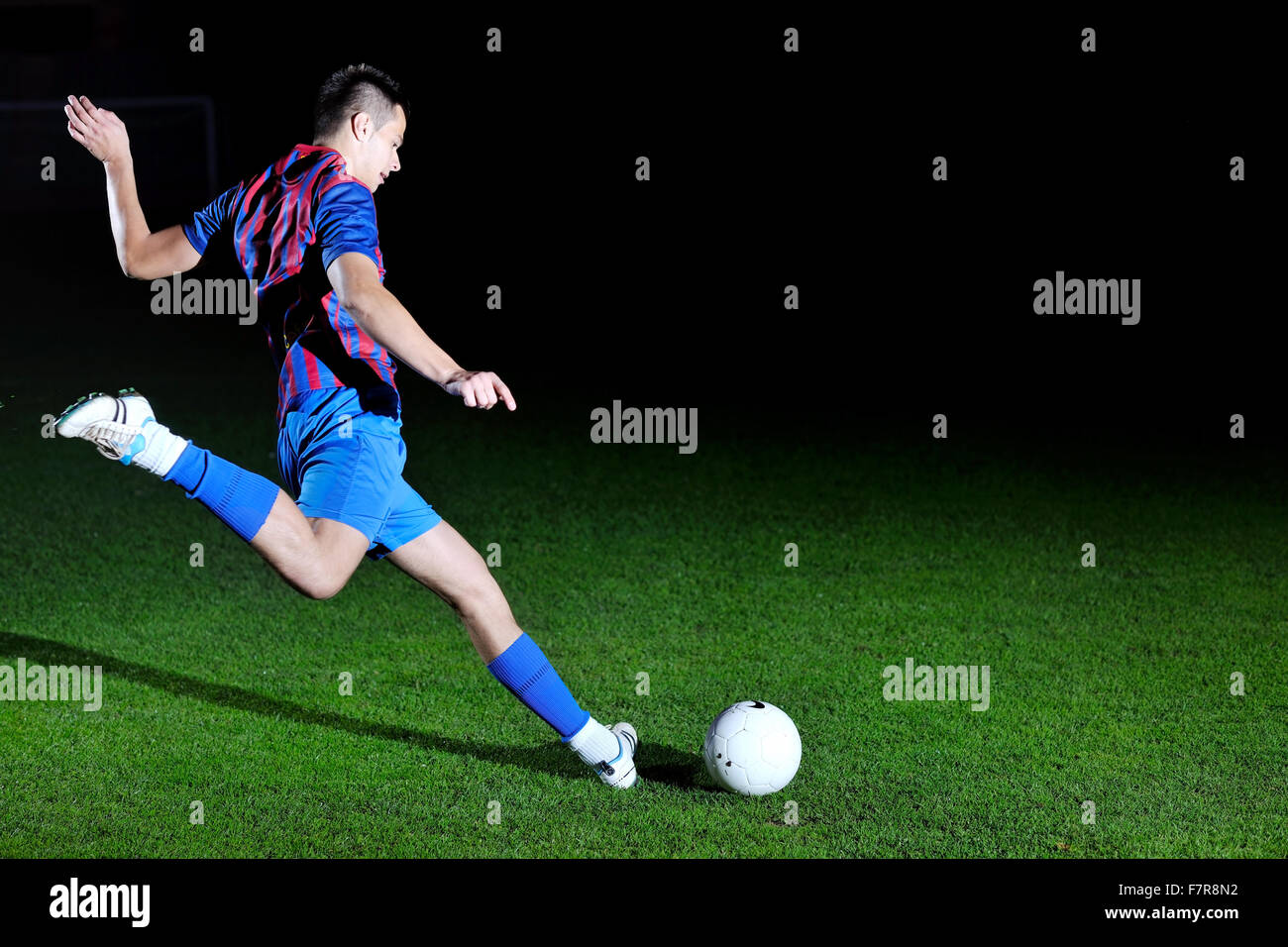 soccer player doing kick with ball on football stadium field isolated ...