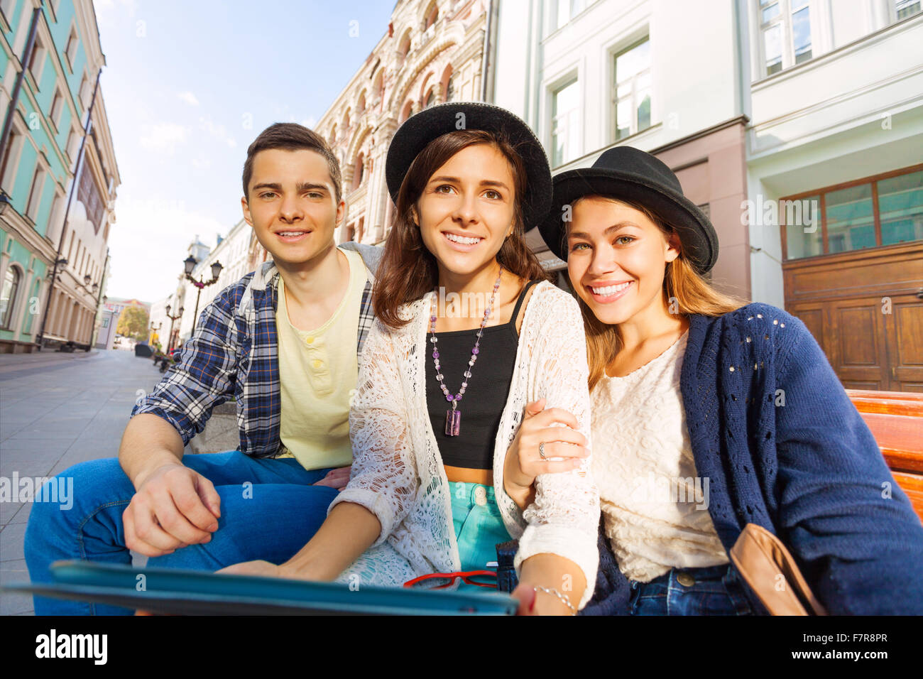 Friends sit on the bench together holding tablet Stock Photo - Alamy