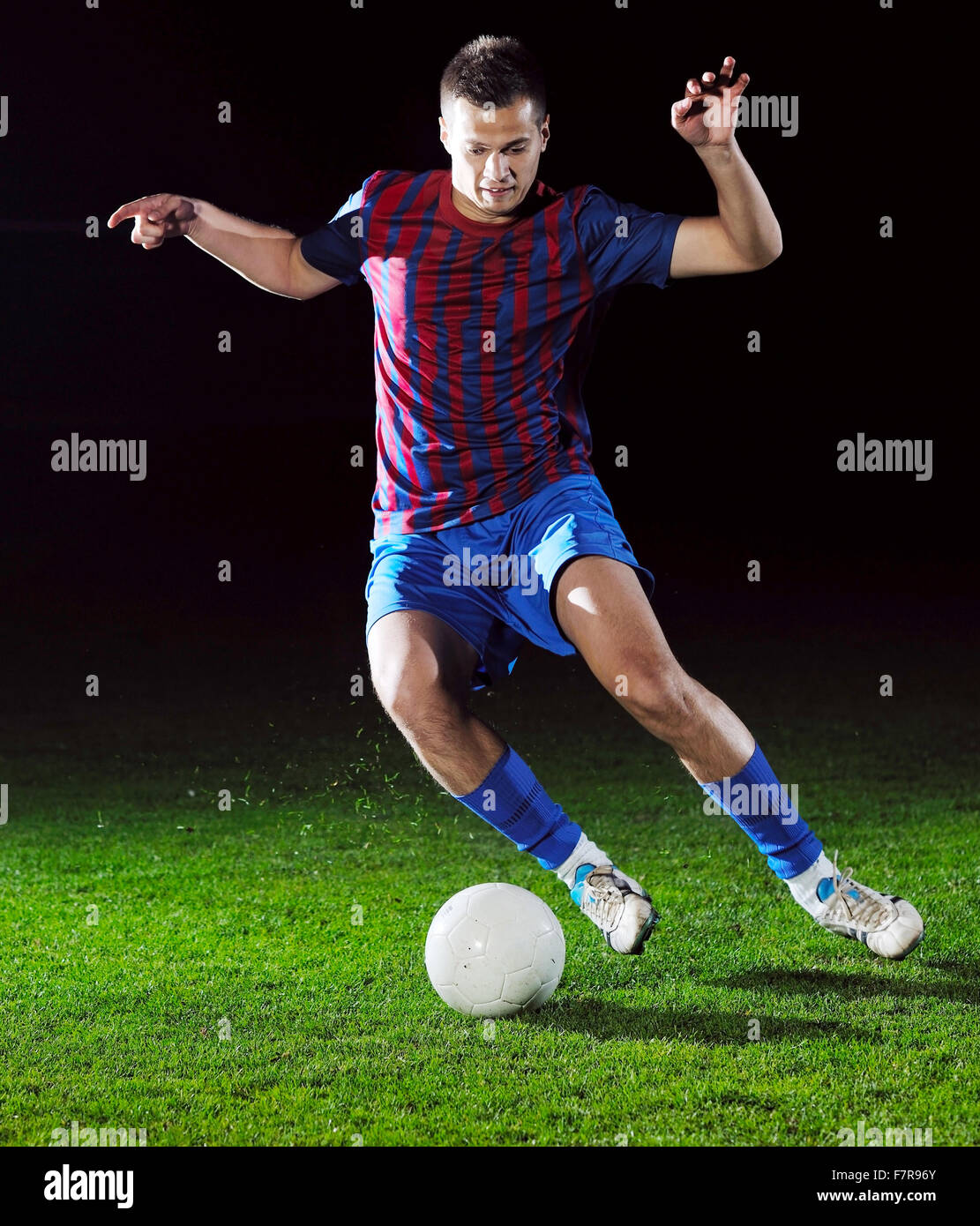 soccer player doing kick with ball on football stadium field isolated ...
