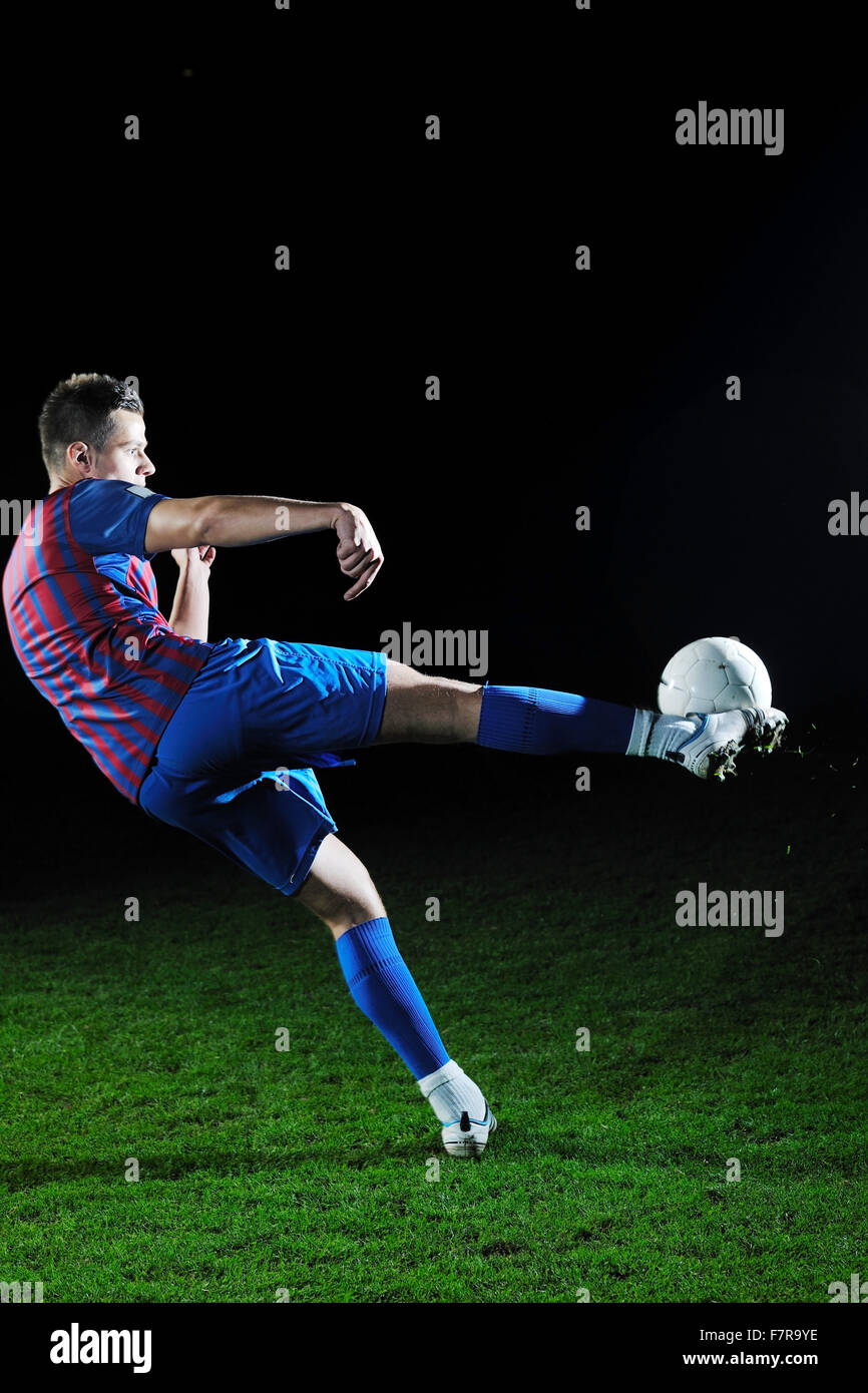 soccer player doing kick with ball on football stadium field isolated on black background in ...