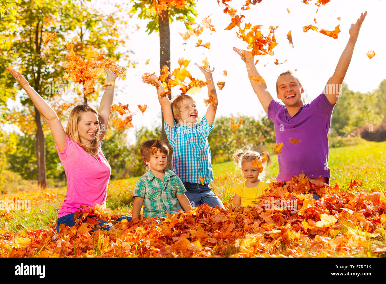 Kids and parents throw leaves in the air sitting Stock Photo - Alamy