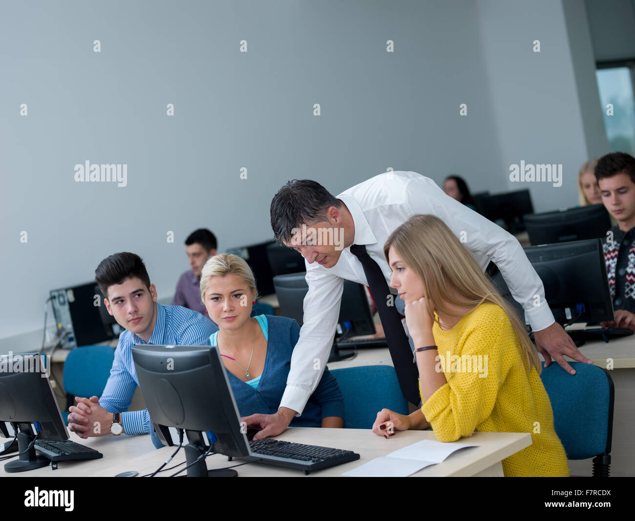 group of students with teacher in computer lab classrom learrning ...