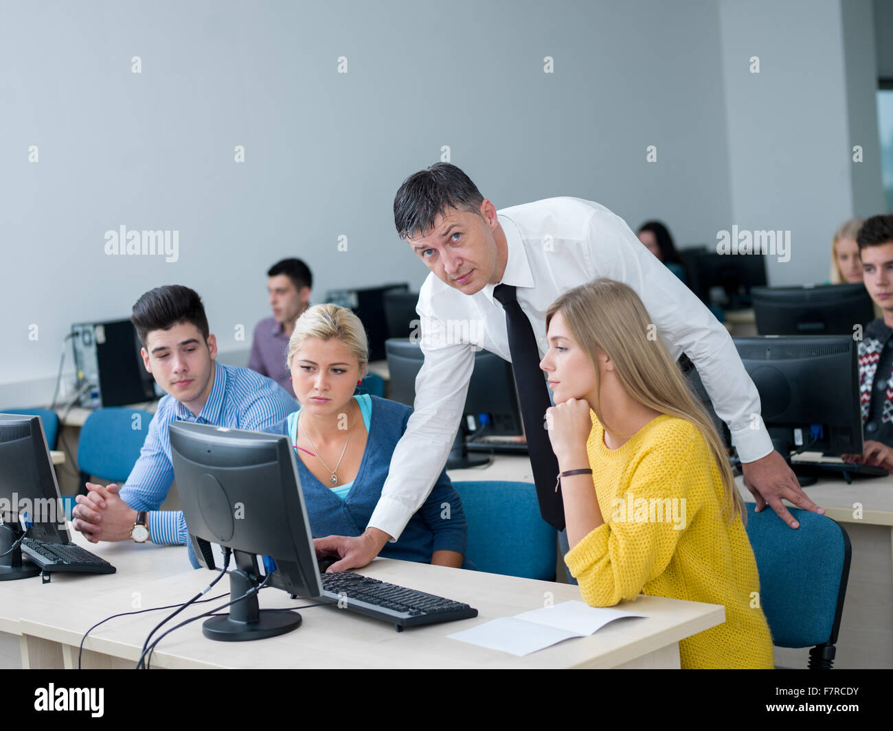 group of students with teacher in computer lab classrom learrning ...