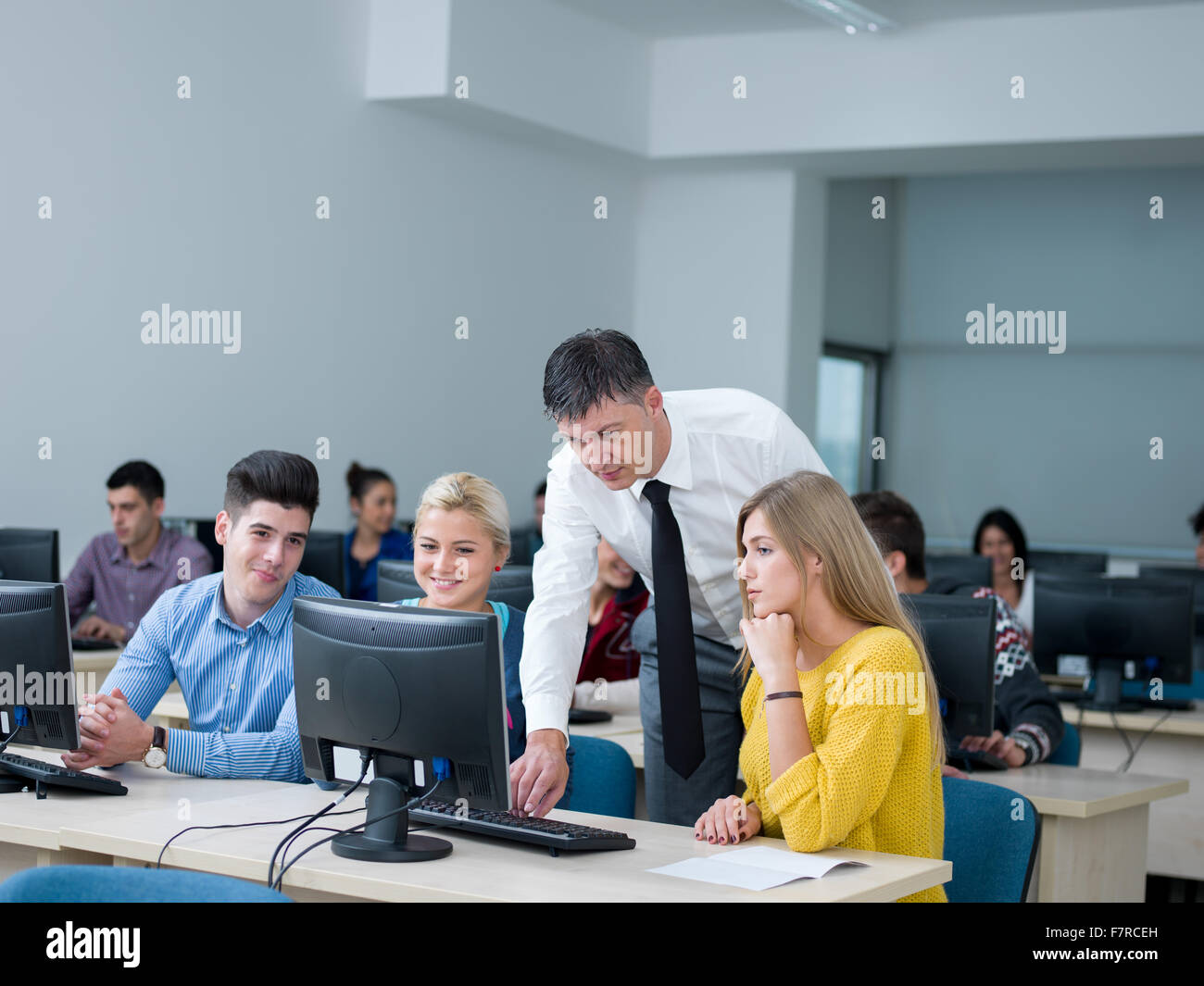 group of students with teacher in computer lab classrom learrning ...