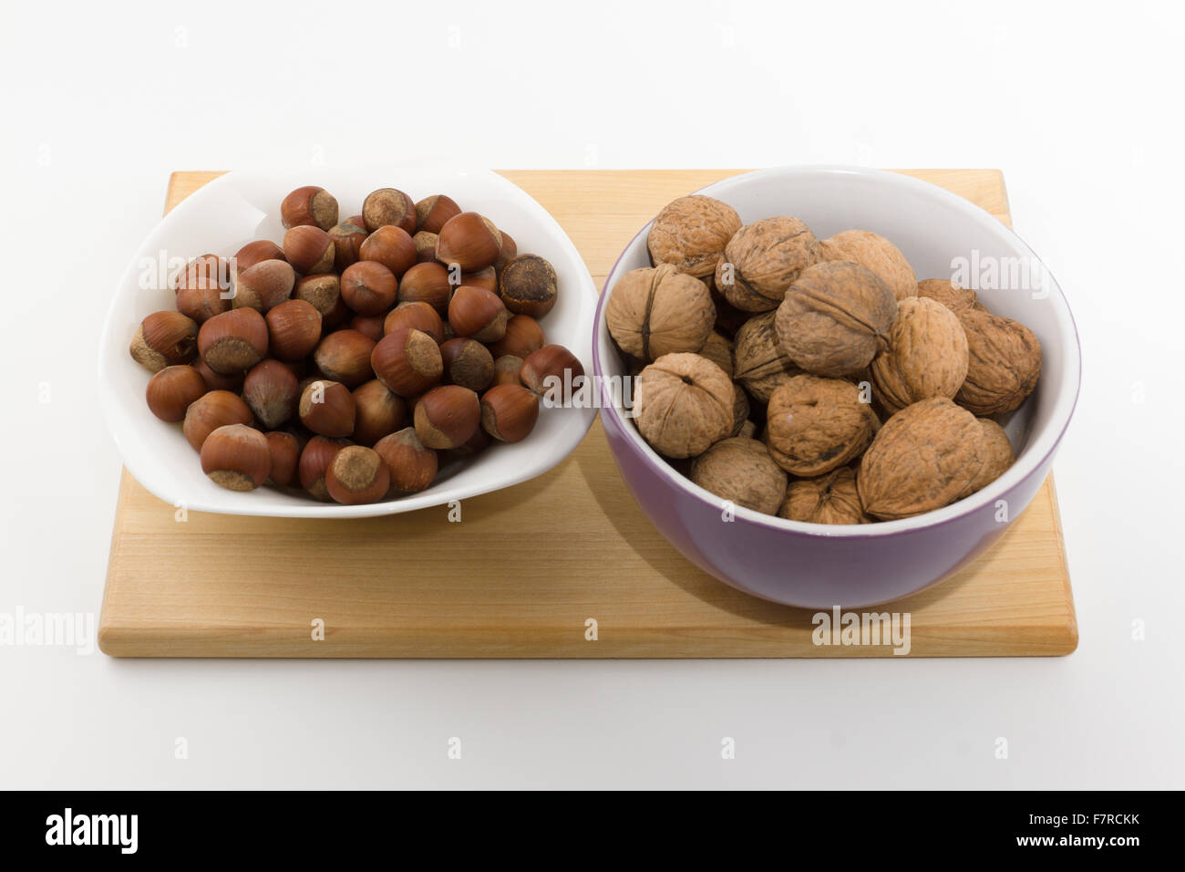 the platefuls of different nuts stand on a plate on a white background ...