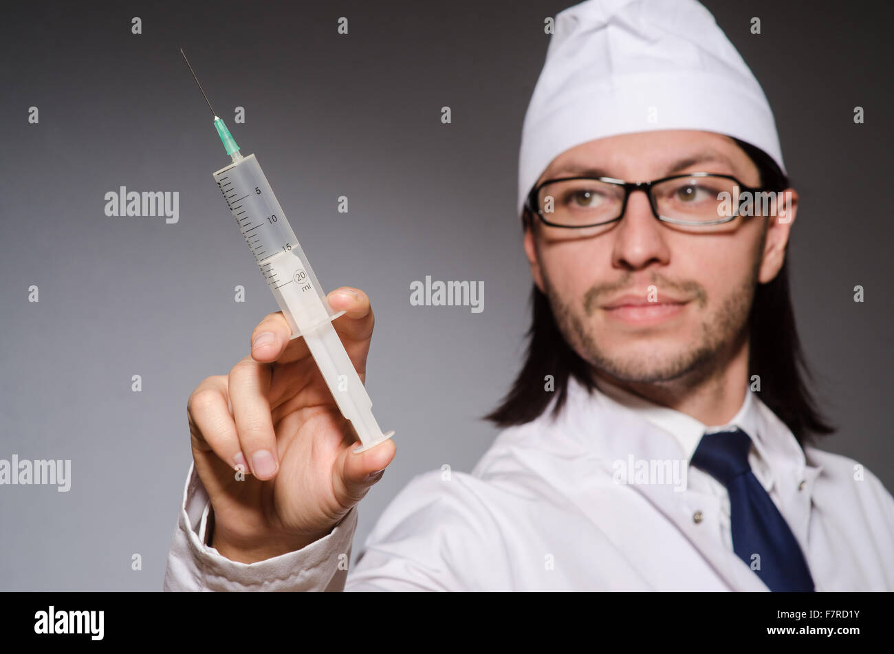 Young doctor man with syringe against grey background Stock Photo - Alamy