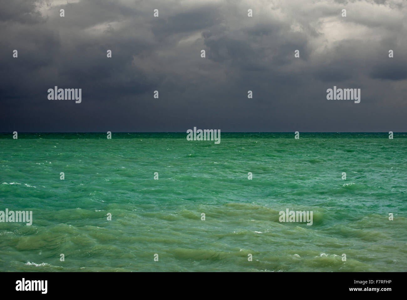 Dark rain clouds over emerald coloured sea water Stock Photo - Alamy