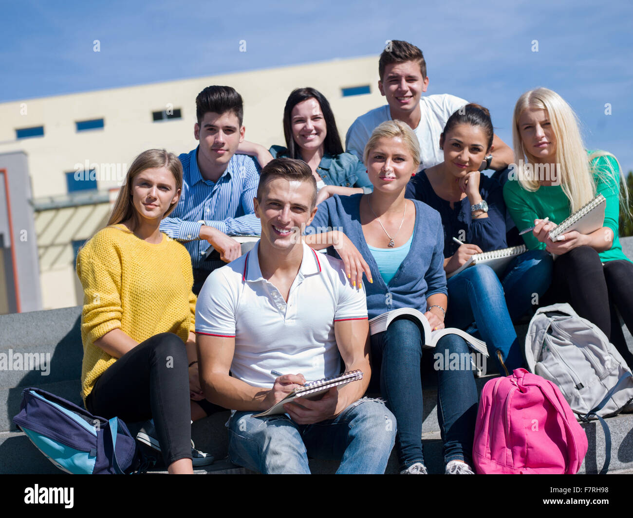 Group portrait of happy students outside sitting on steps have fun ...